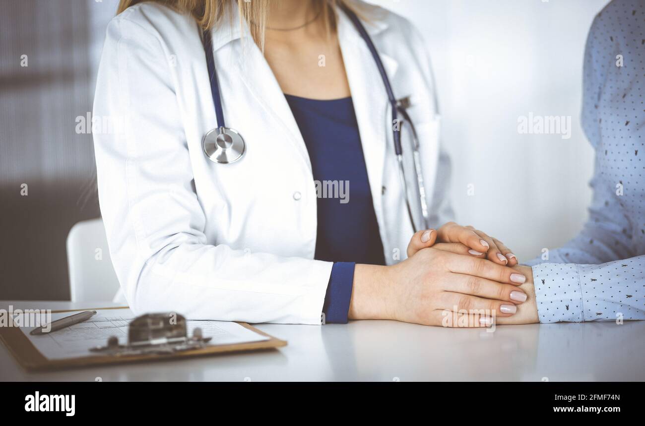 Unknown woman-doctor is holding her patient's hands to reassure a ...