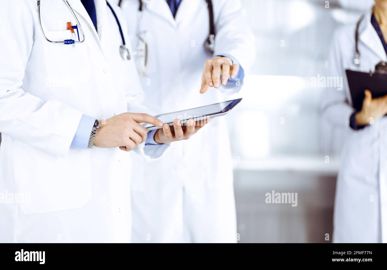 Group of unknown doctors use a computer tablet to check up some medical ...