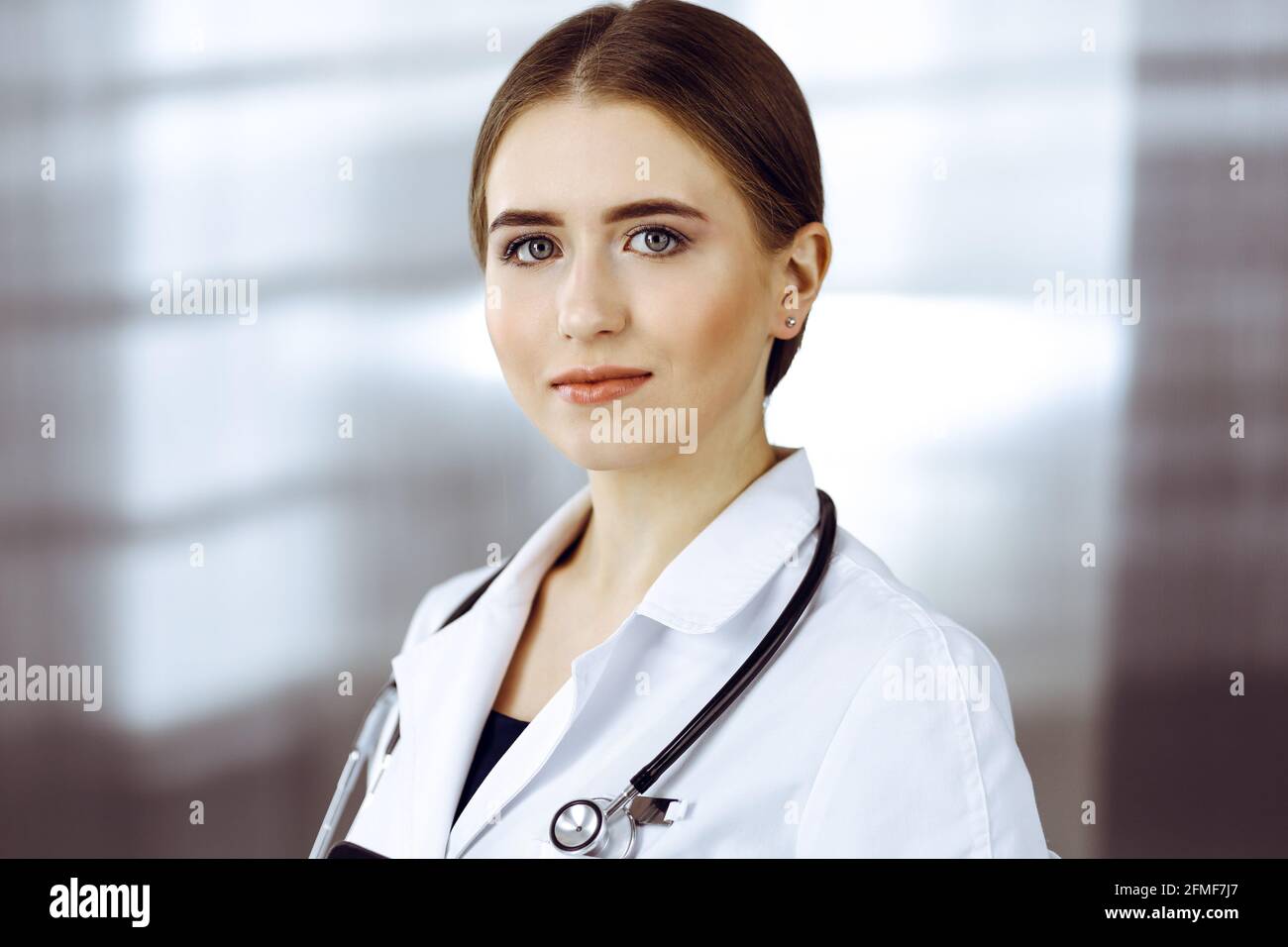 Friendly female doctor standing and holding clipboard in modern clinic ...