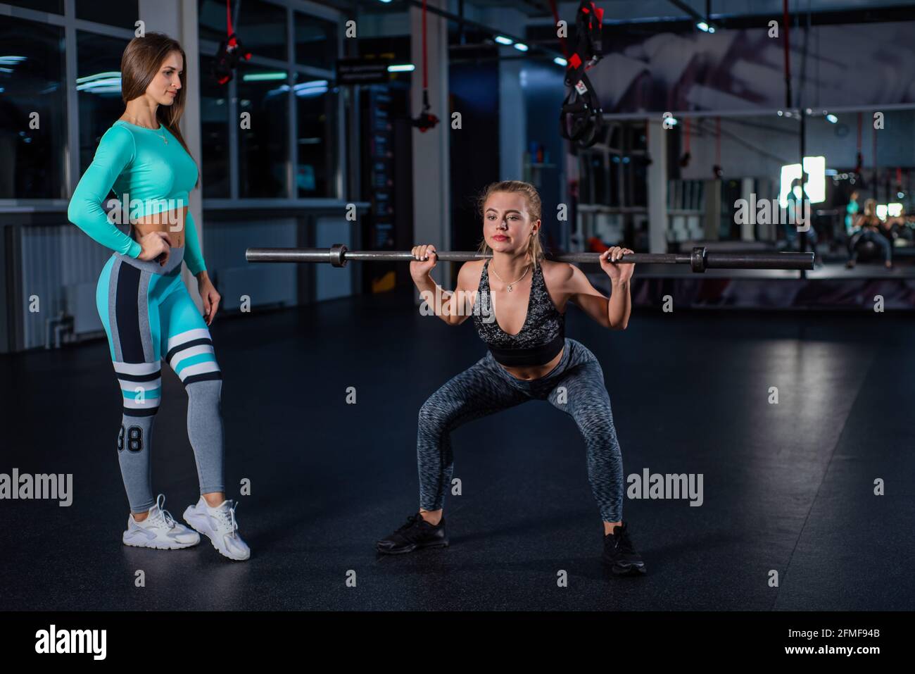 Young athletic girl doing barbell squats in the gym under the ...