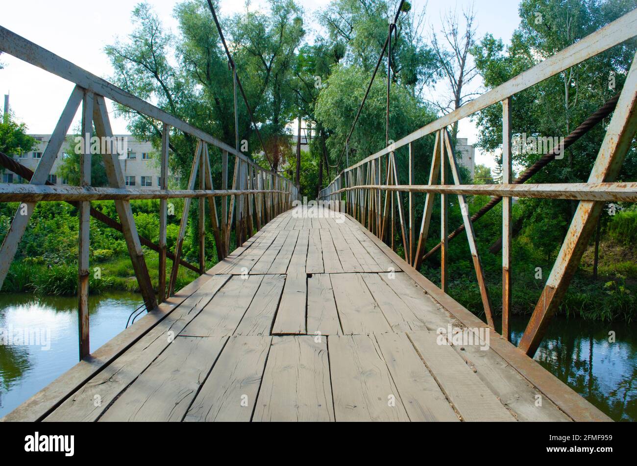 A pedestrian steel bridge with handrails and a wooden floor passes ...