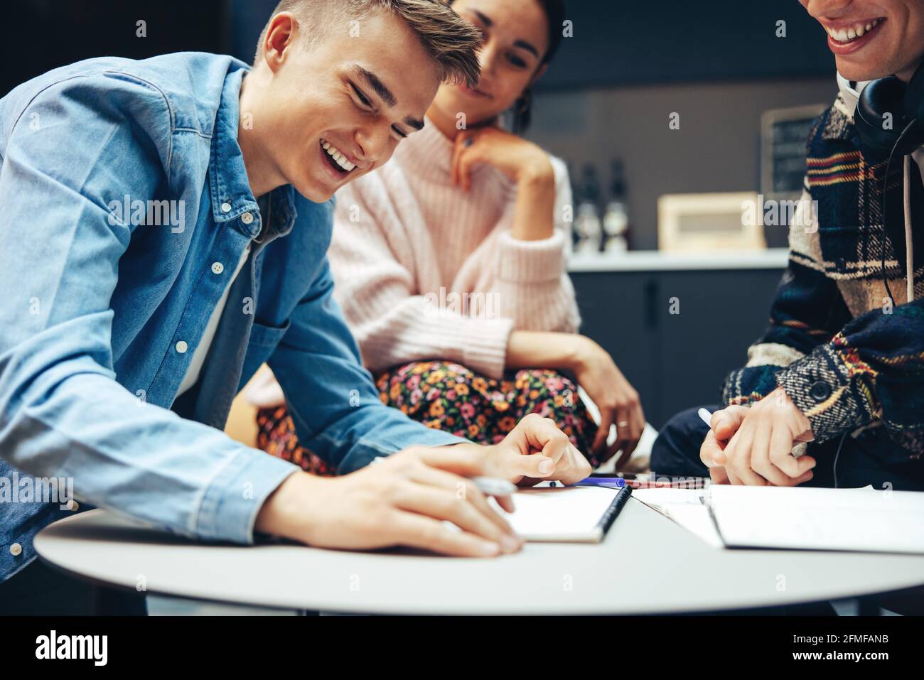 college students doing project in library. Young man writing in book ...