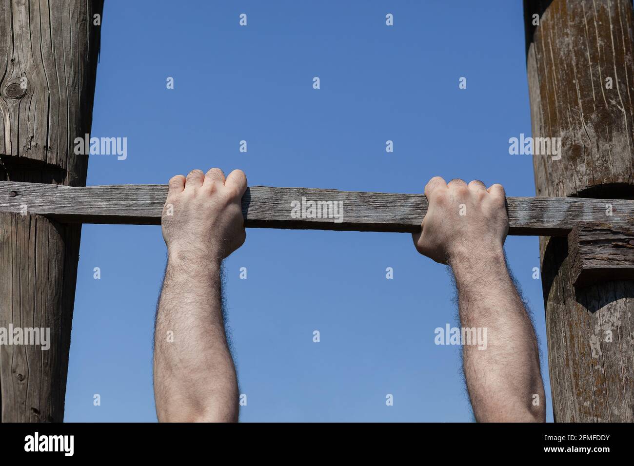 Strong male hands firm gripping wooden ladder step, hanging, blue sky ...