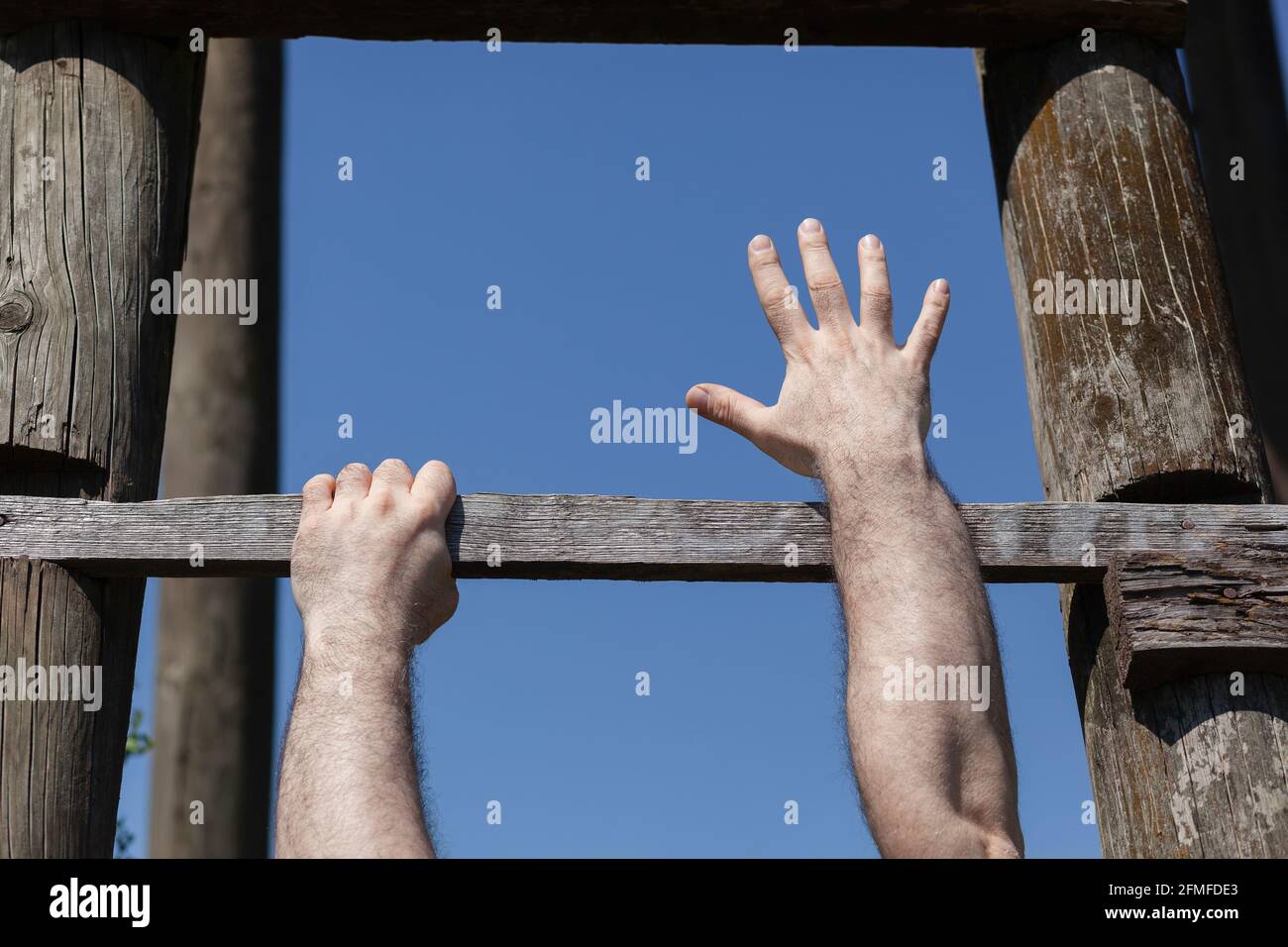 Strong male hands firm gripping wooden ladder step, one hand reaching ...