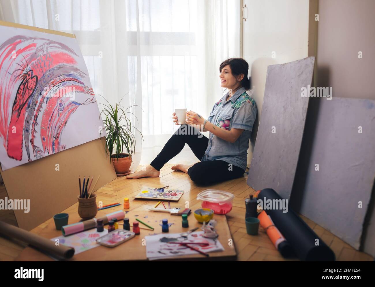 Portrait of female artist with coffee cup in studio. Creative activity ...