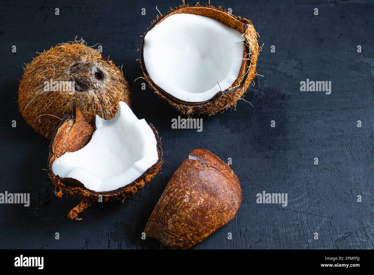 Coconut cut in half on a black background Stock Photo - Alamy