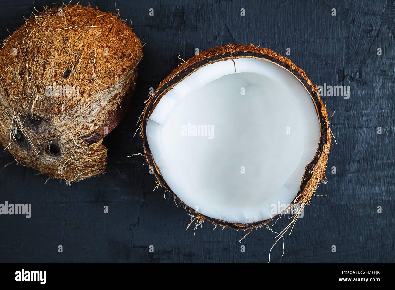 Coconut cut in half on a black background Stock Photo - Alamy