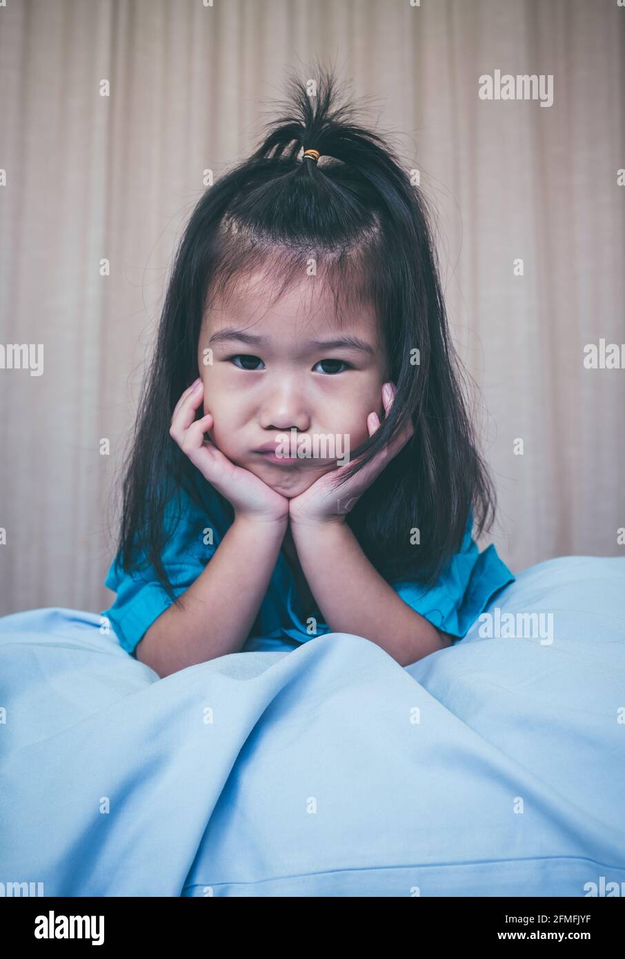 Illness asian child on sickbed and looking at camera, admitted in hospital. Unhappy girl feeling ...