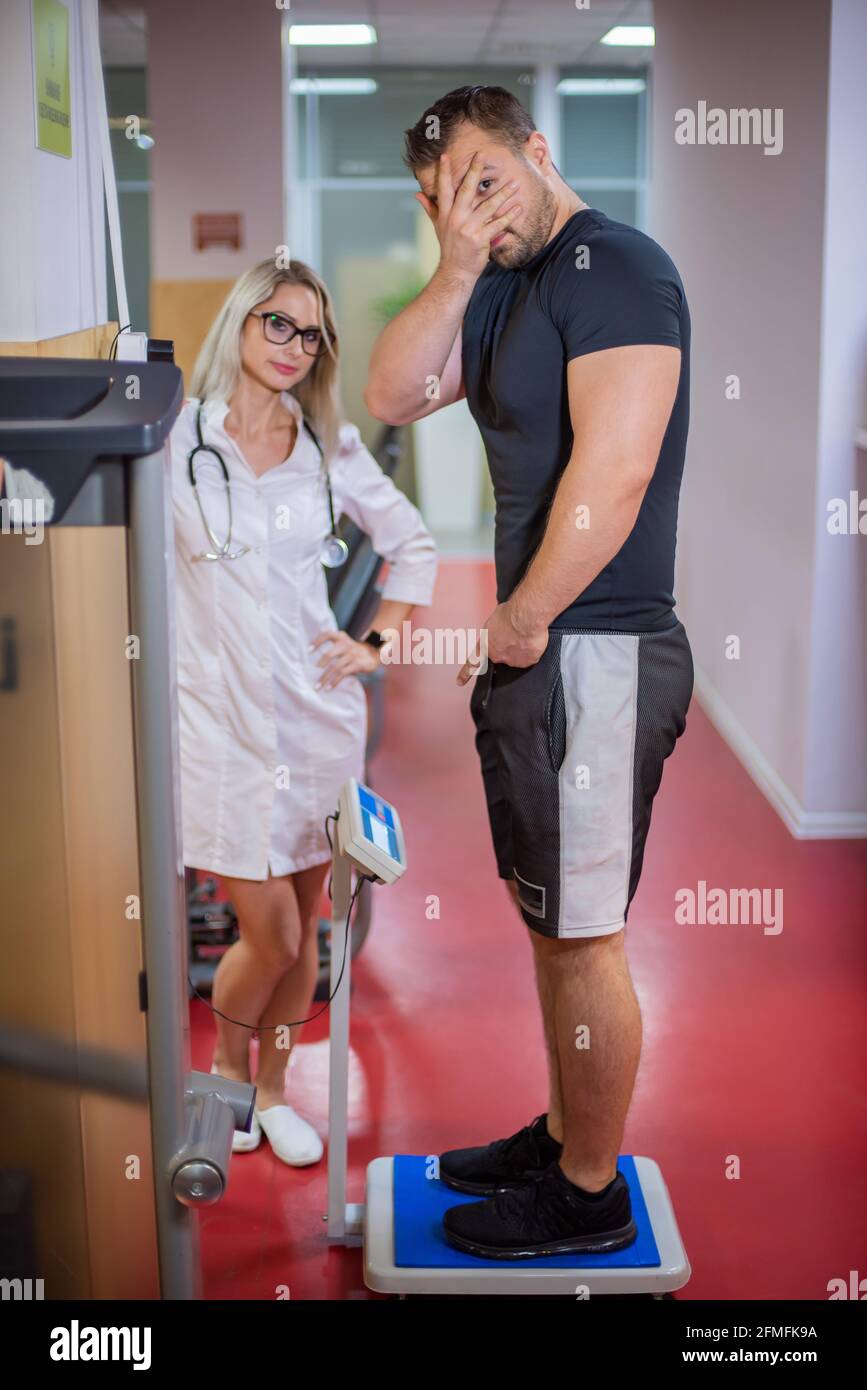 The athlete in the gym controls the treadmill exercises of a beautiful ...