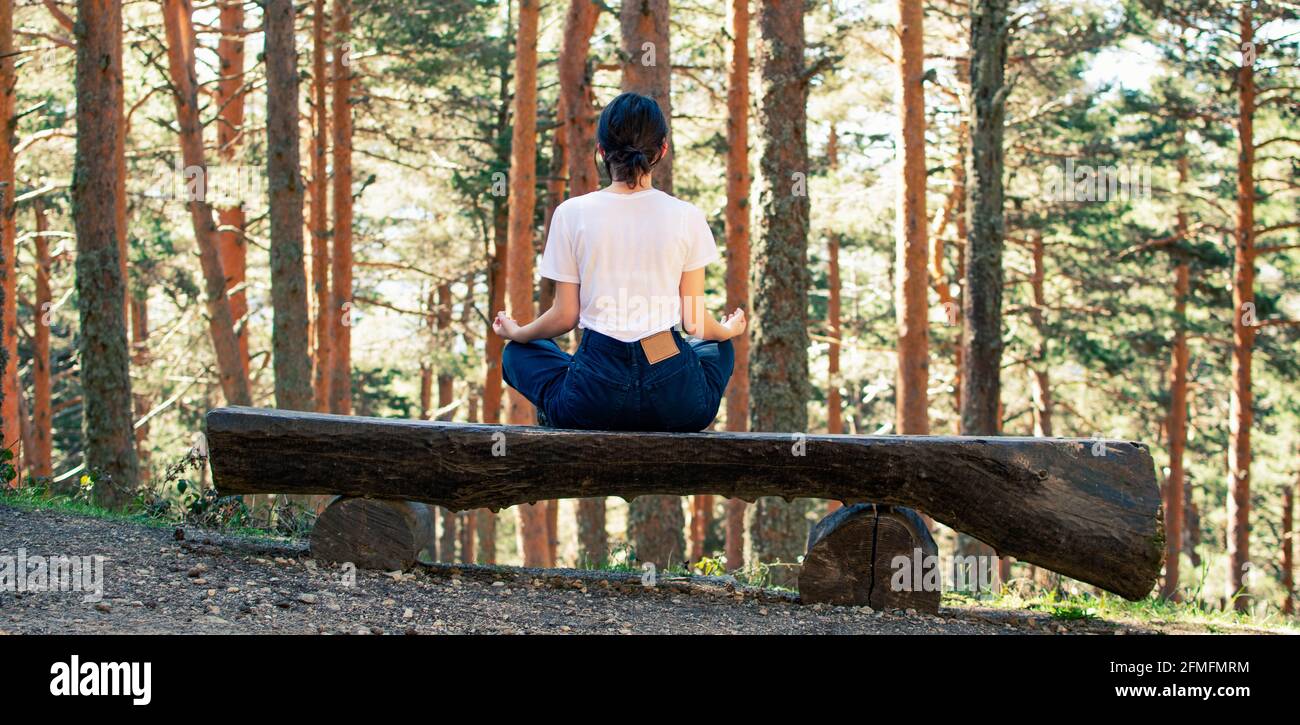 A young woman sitting on her back on a bench while doing yoga in the ...