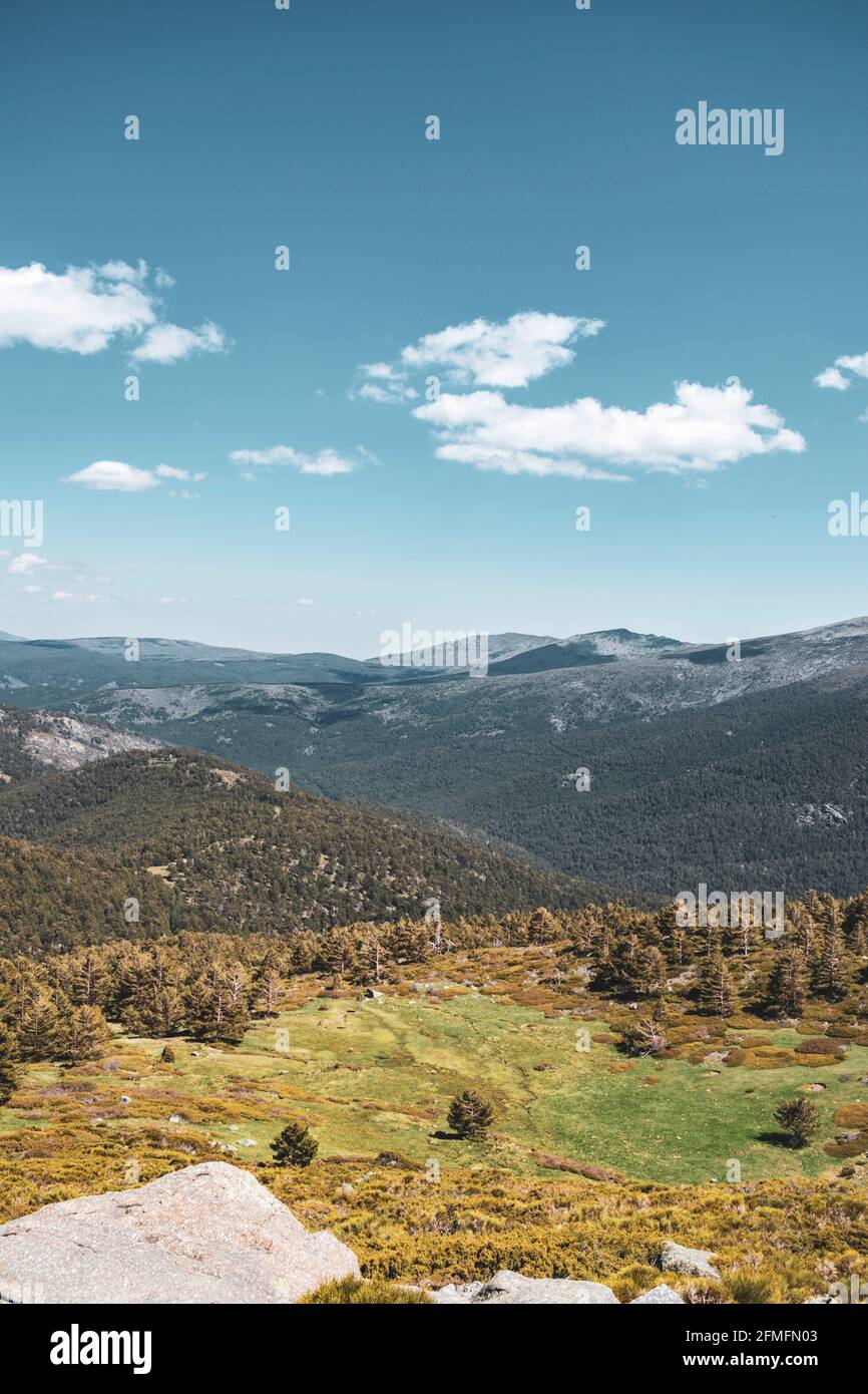 Vertical mountain landscape with large clouds casting their shadows on ...