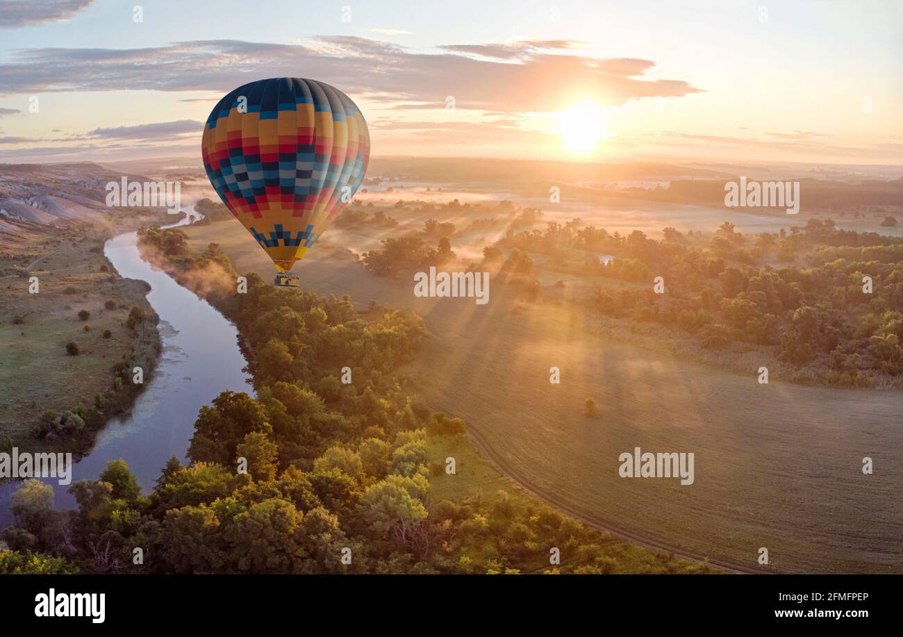 Hot air balloon over river on sunset Stock Photo - Alamy