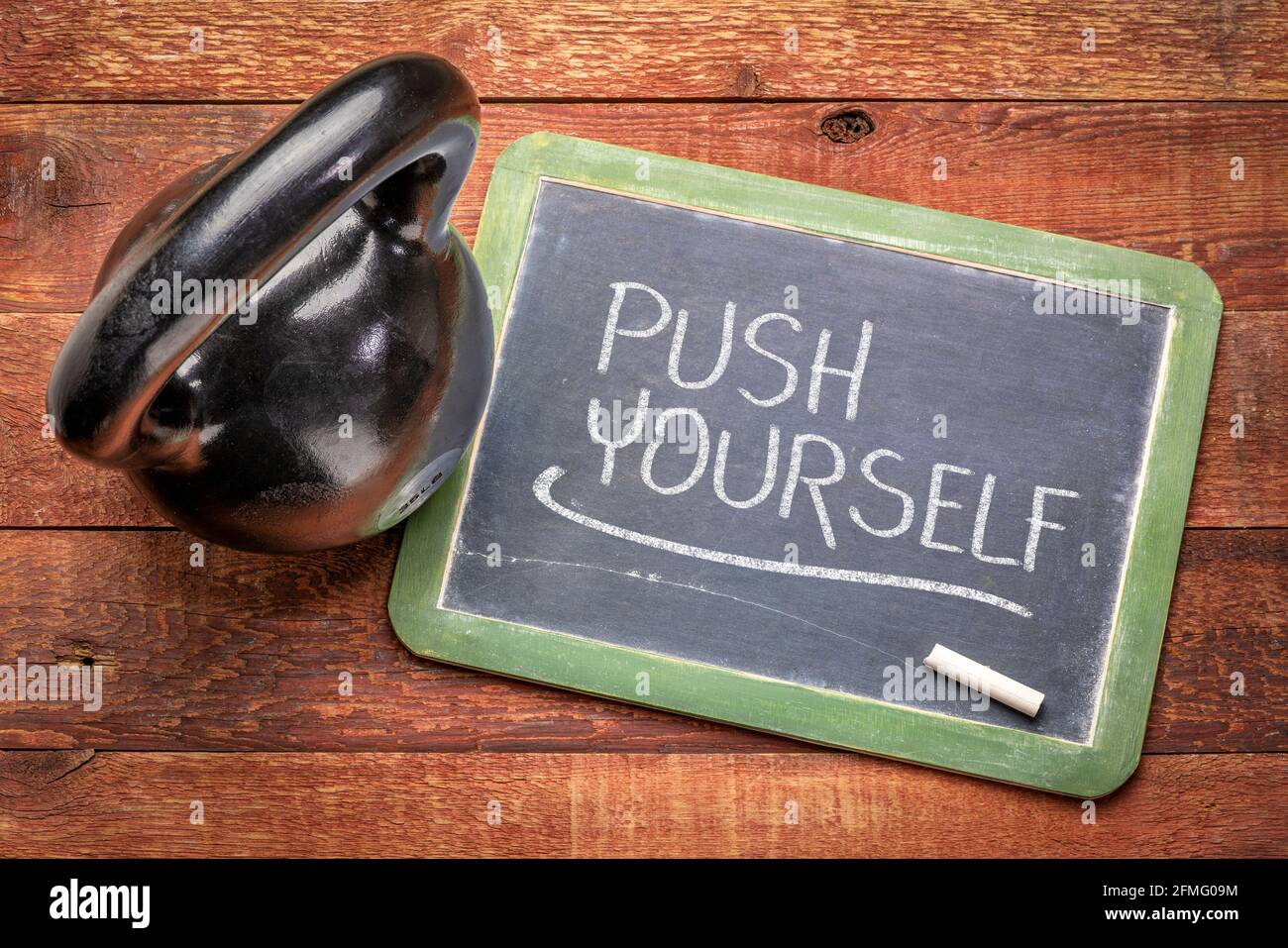 push yourself - white chalk text on a slate blackboard with a ...
