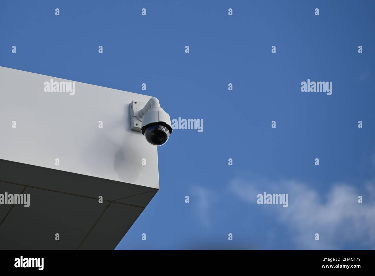 A white dome security camera, part of a CCTV system, attached to a ...