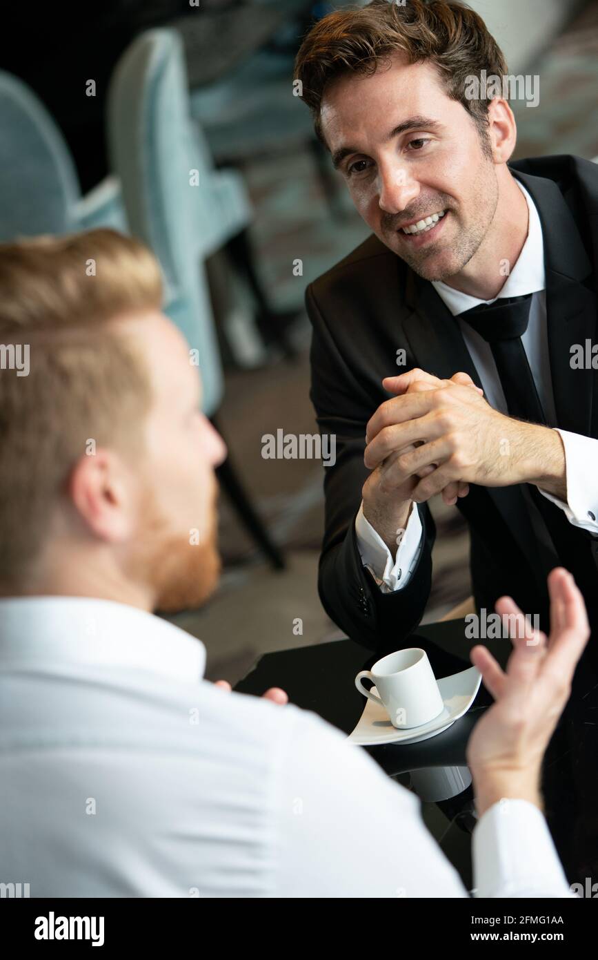 Colleagues and friends. Two cheerful businessmen drinking coffee and ...