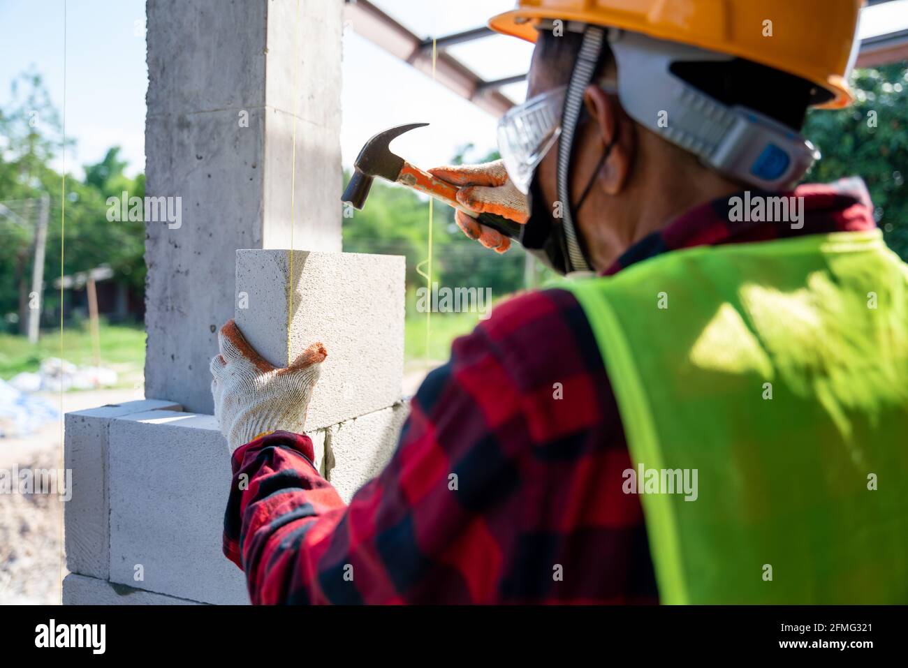 Close-up of bricklayer builder use a hammer to help with autoclaved ...