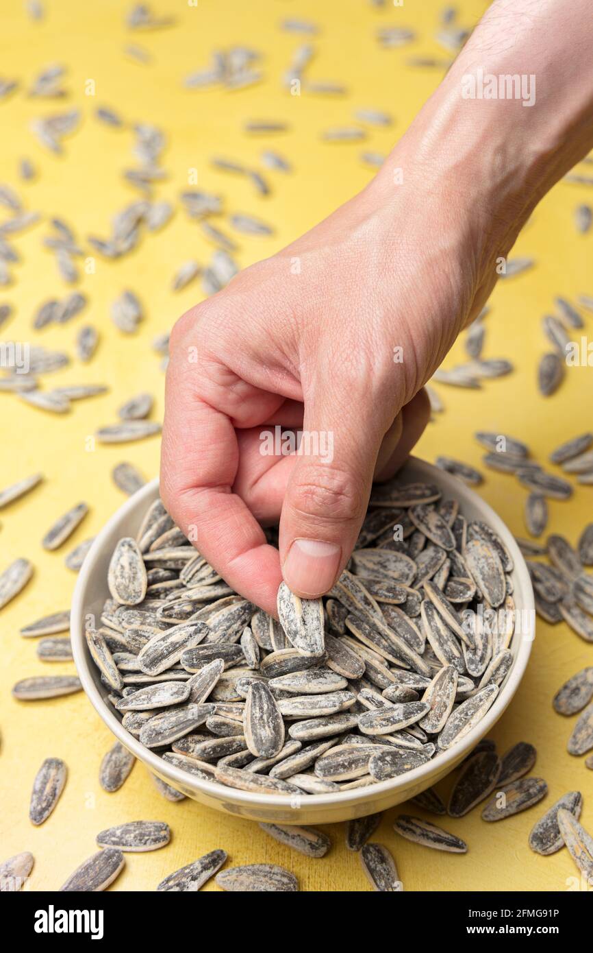 Hand picking up a sunflower seed from a bowl Stock Photo - Alamy