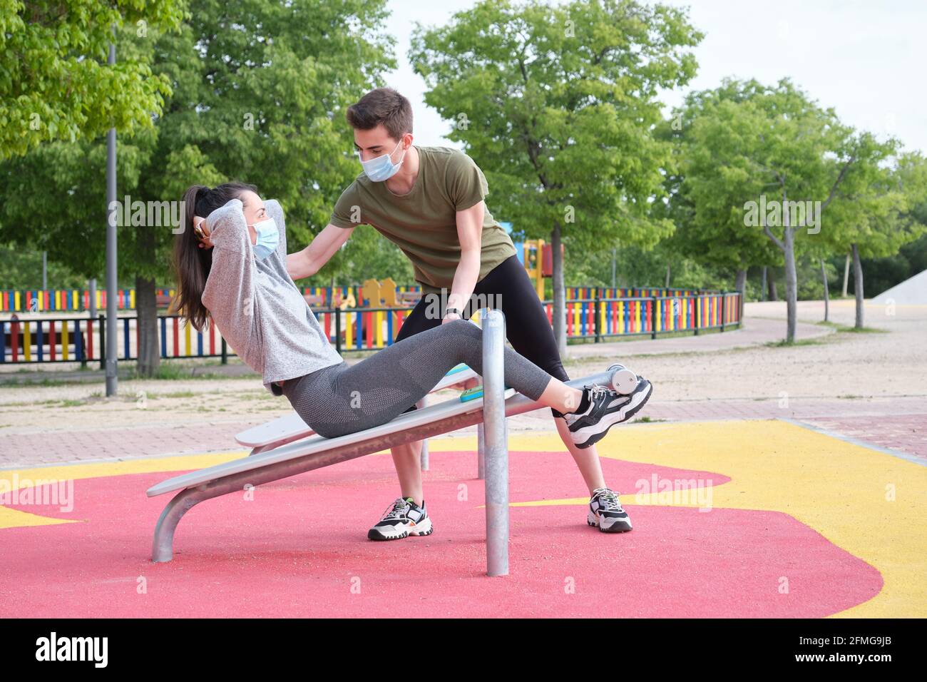 A woman doing abdominal crunches with her personal trainer at a ...