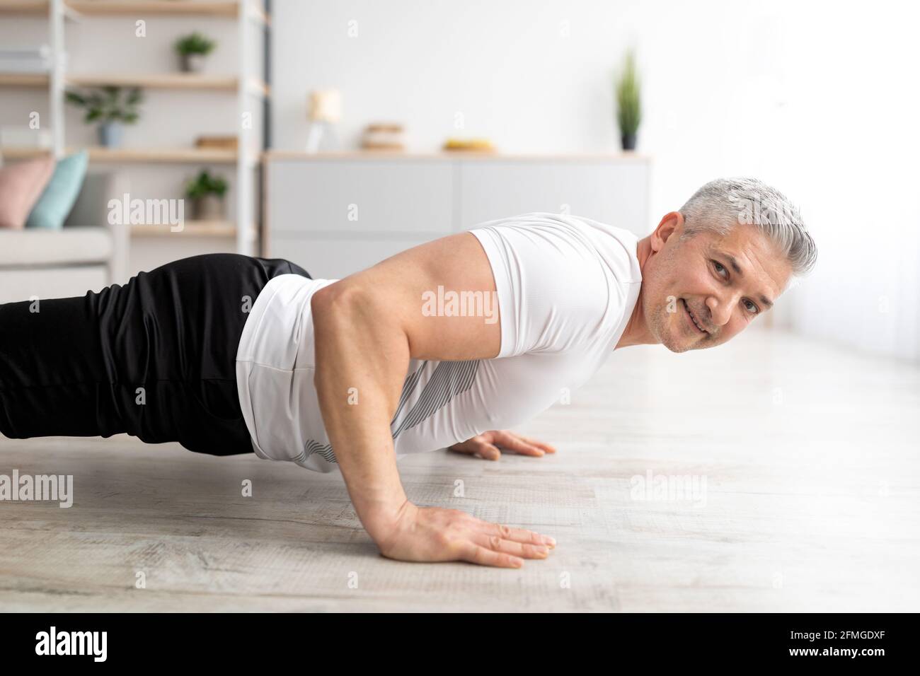 Active lifestyle. Sporty mature man doing push-ups or plank exercise on ...