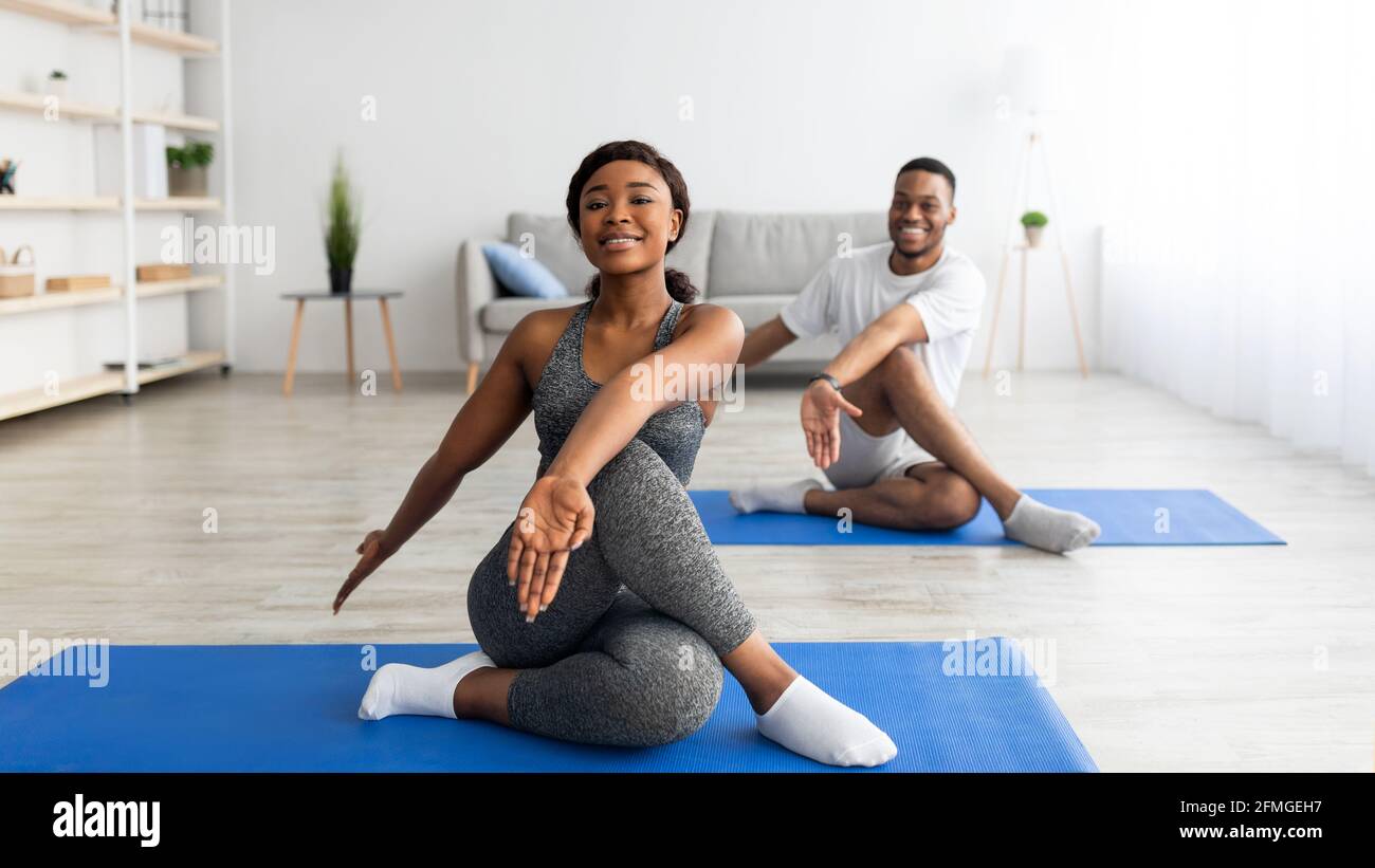 Flexibility exercises for healthier living. Athletic black couple doing ...