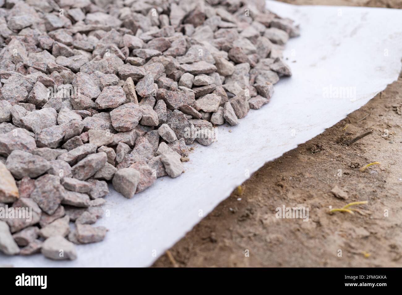 Construction crushed stone is poured and compacted on agrofibre before ...