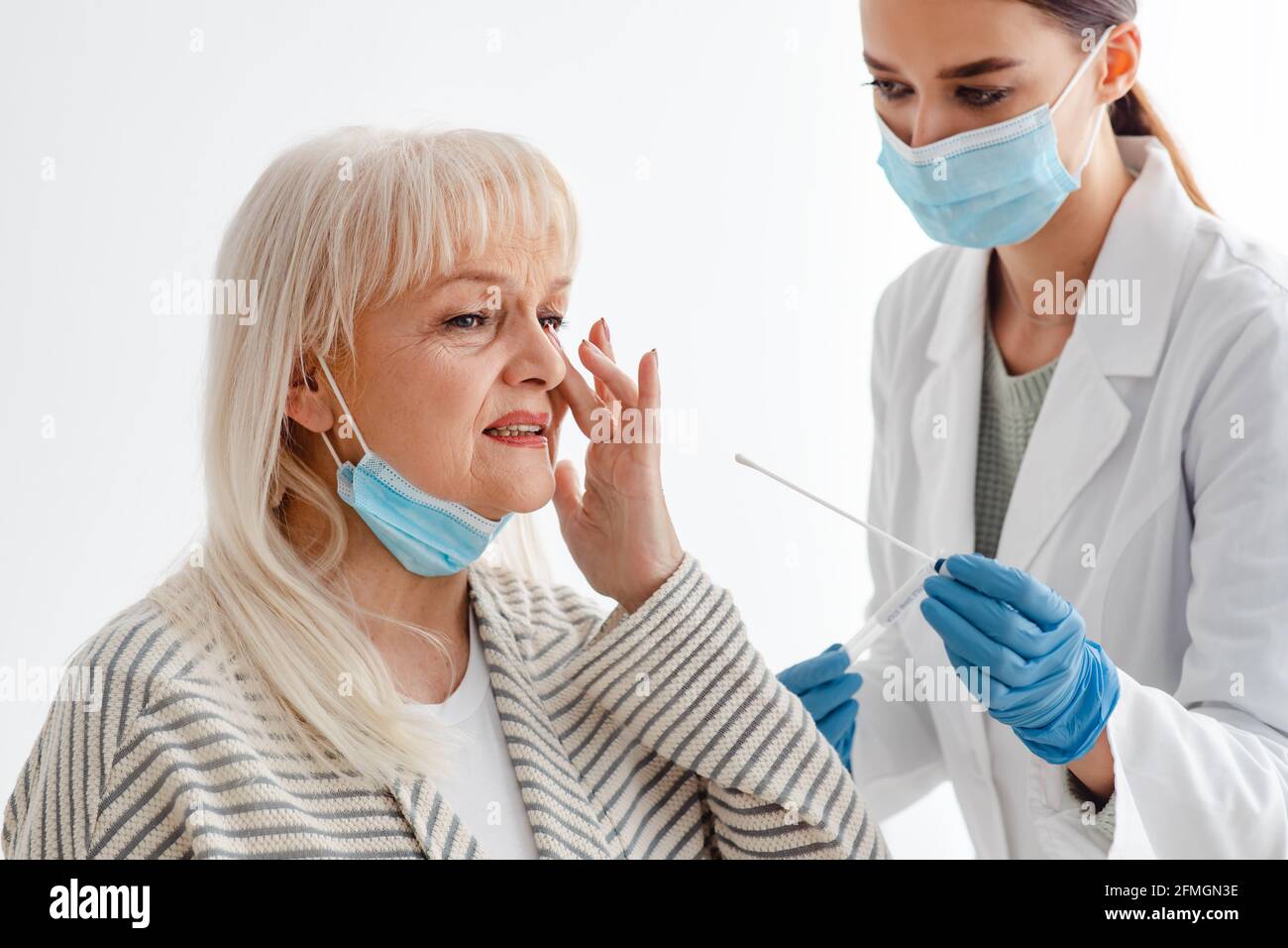 Doctor taking PCR test sample from potentially infected mature lady ...