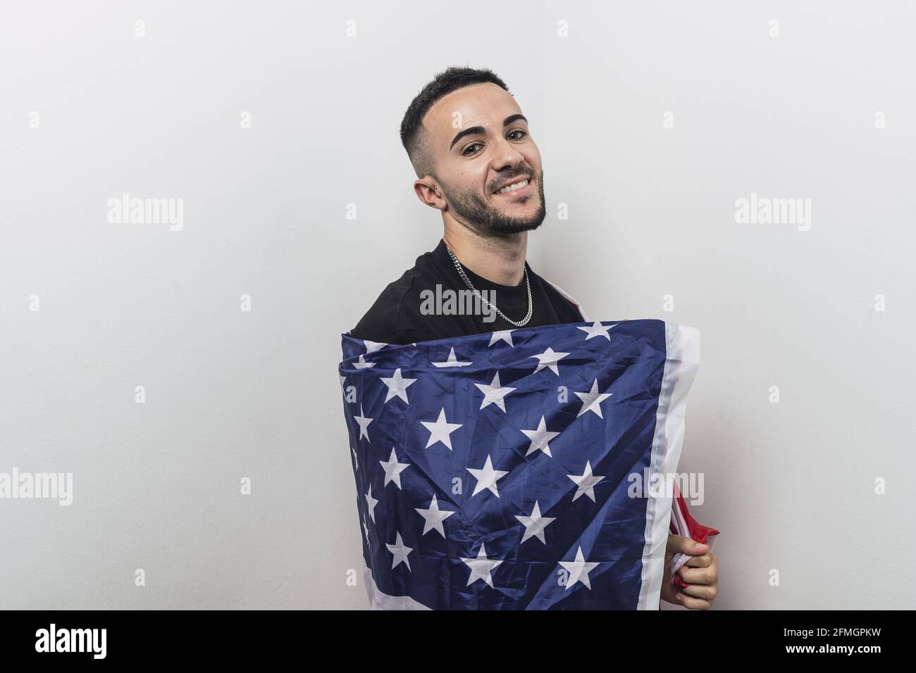 A young handsome Spanish male wrapped in an American flag posing ...