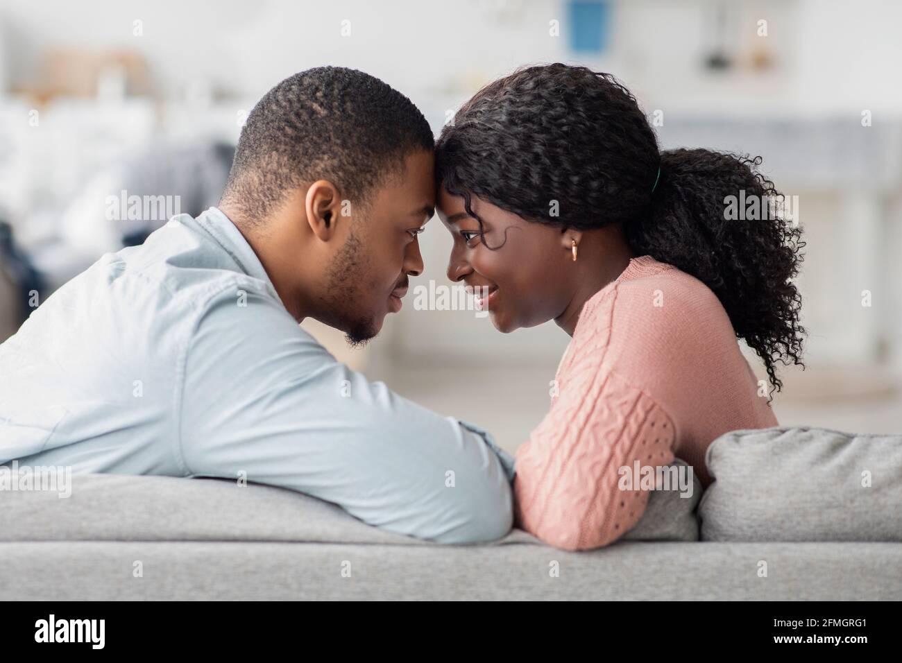 Loving black couple cuddling on couch at home Stock Photo - Alamy