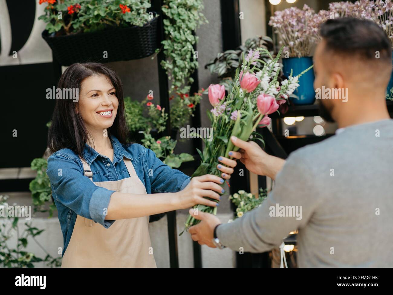 Work of seller with client in plants shop outdoor. Modern successful ...