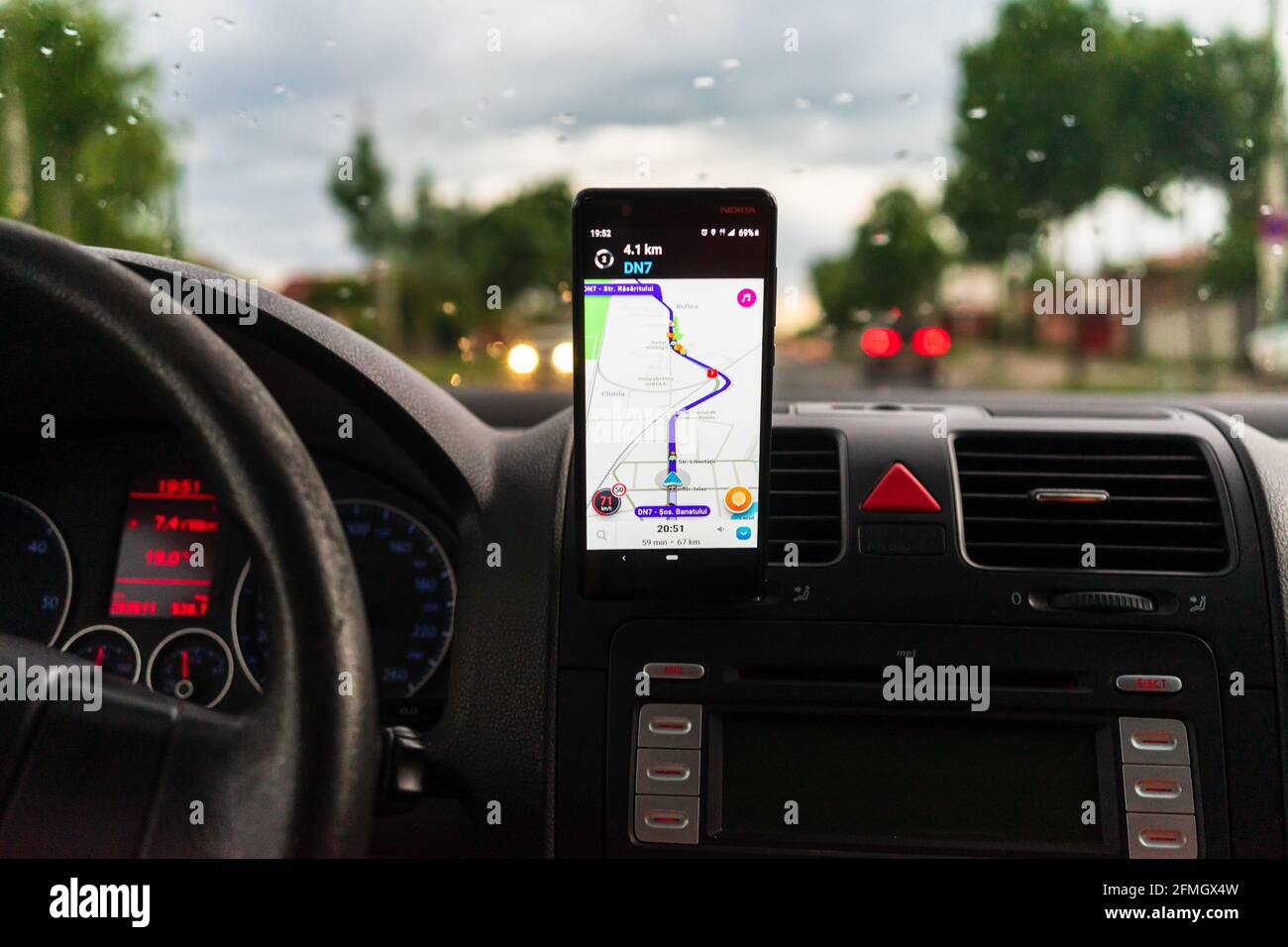 Driving and using waze maps application on smartphone on car dashboard ...