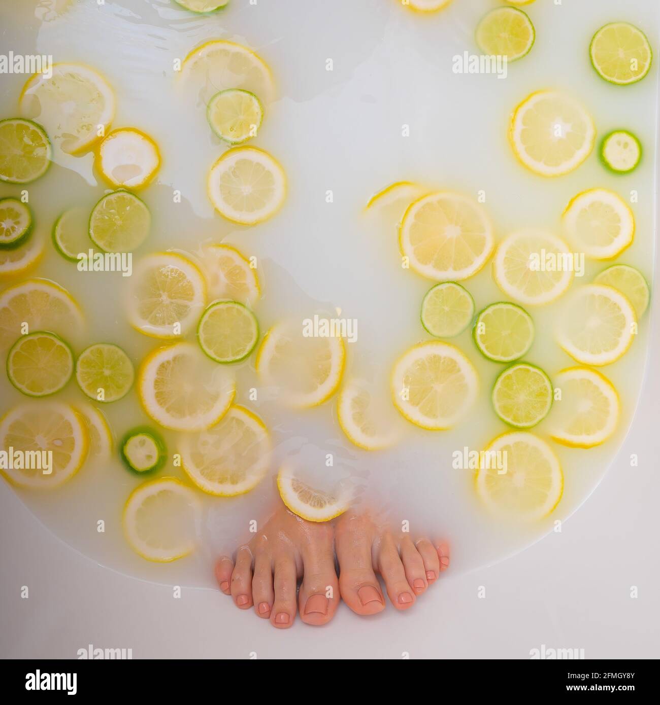 Girl takes a milk bath with lemons and limes. Citrus spa. Body care ...