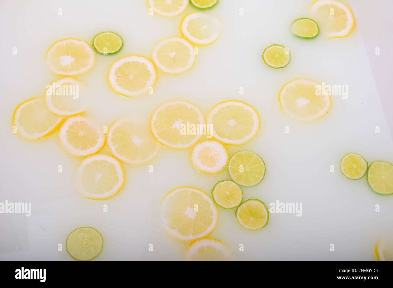 Turbid soapy water in the bath with slices of lemon and lime top view ...