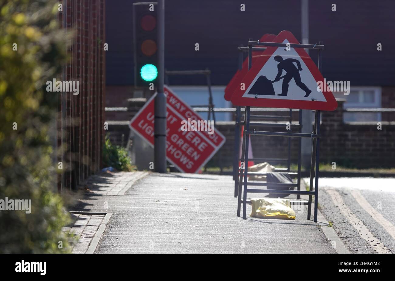 A triangular construction sign on the road next to traffic lights Stock ...