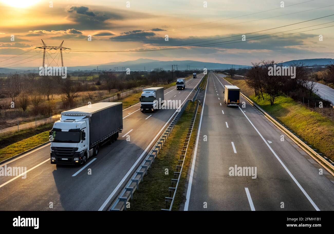 Sunset Highway transit. Convoy or caravan of transportation trucks ...