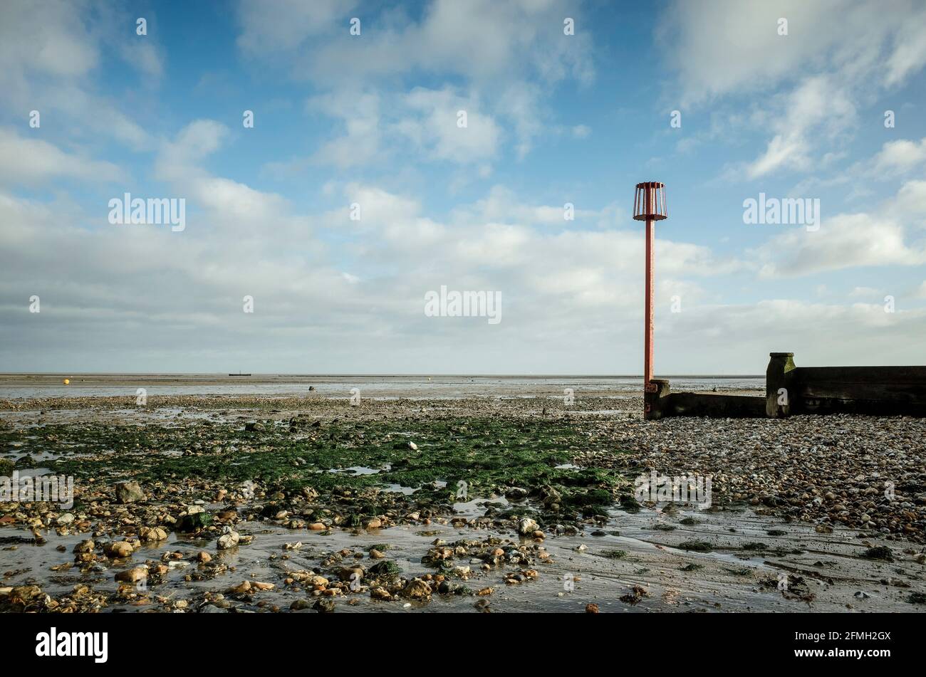 A red painted port lateral mark or channel marker on the shingle beach ...