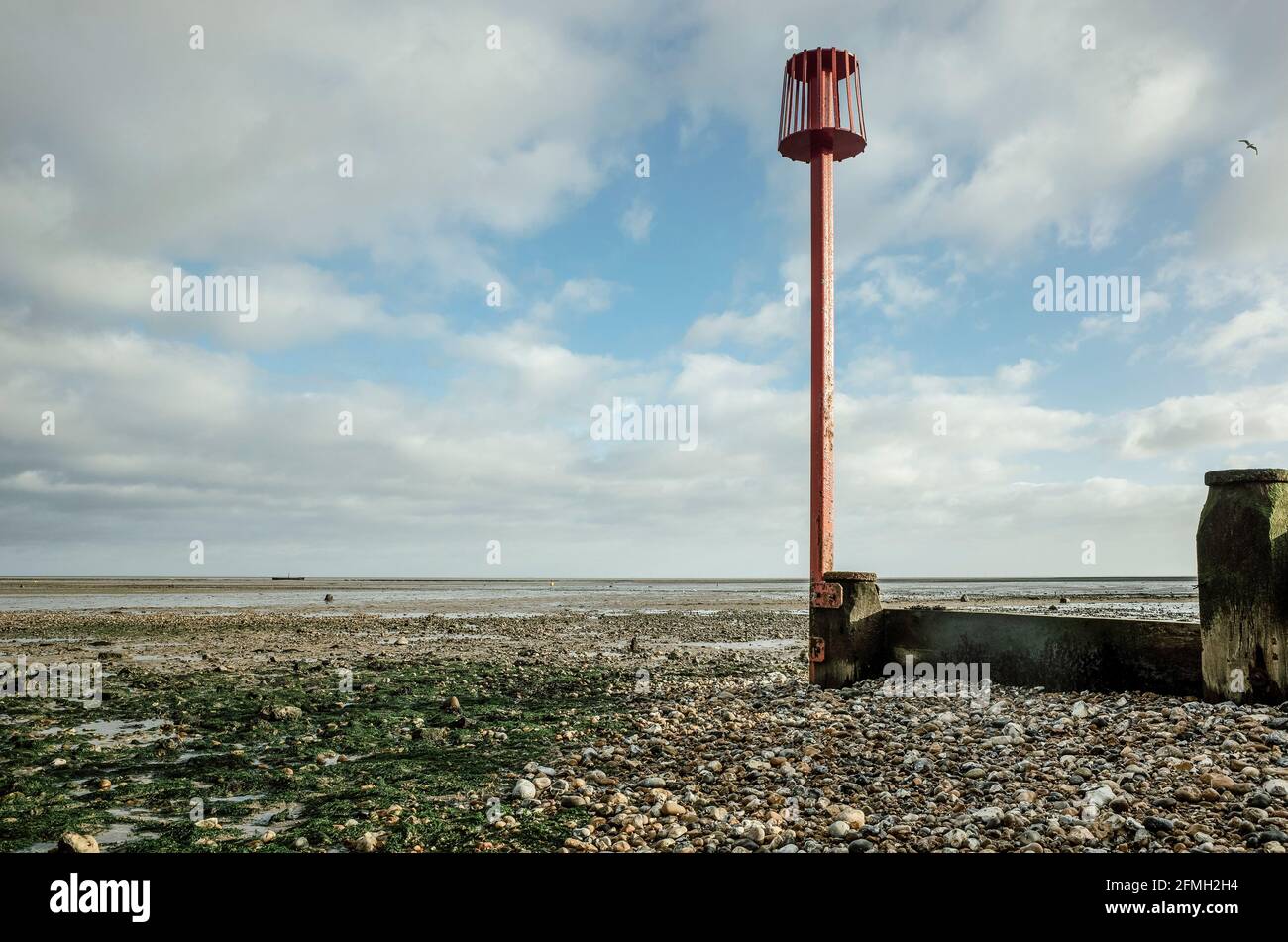 A red painted port lateral mark or channel marker on the shingle beach ...
