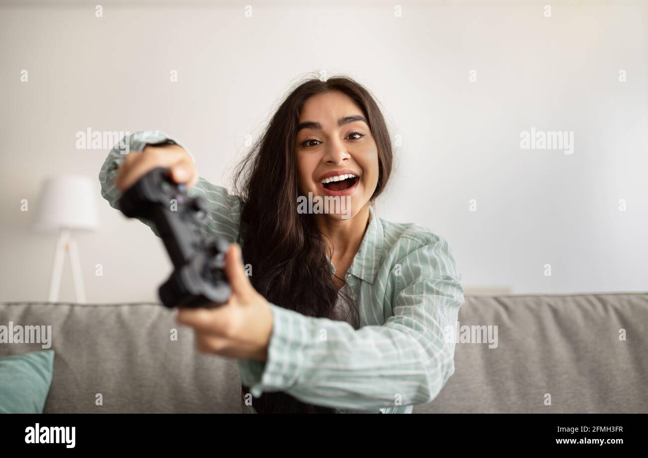 Cheerful Indian woman enjoying videogame on playstation, having fun ...