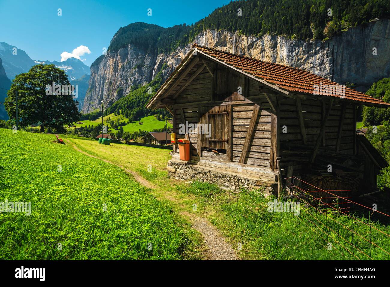 Typical alpine wooden barn on the green pasture and high cliffs in ...