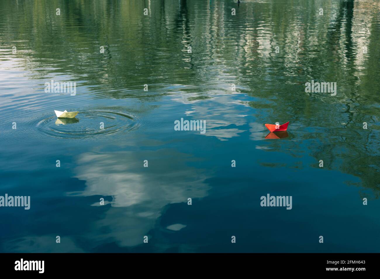 Red and white paper boats float on the water Stock Photo - Alamy