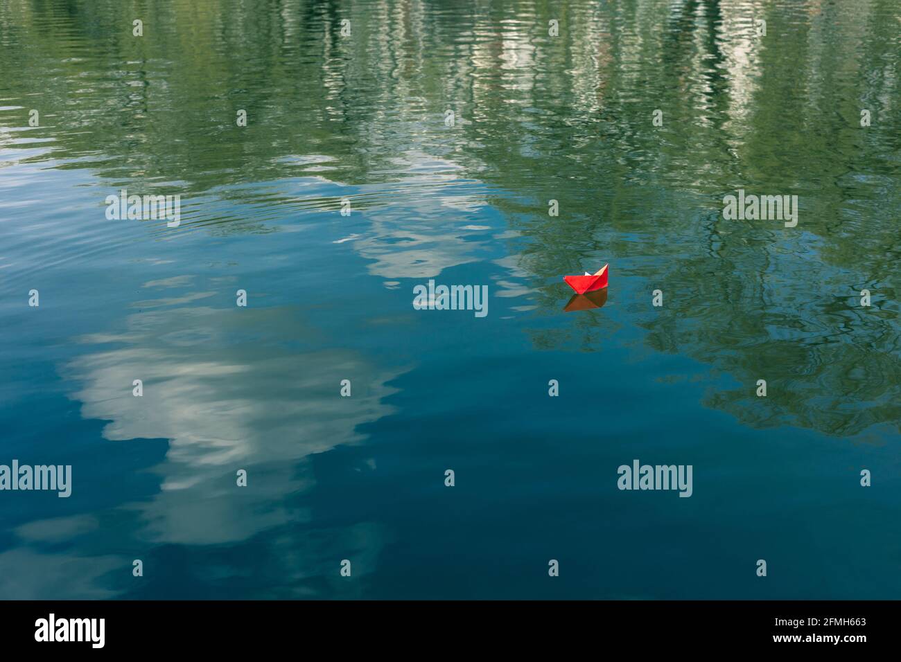 Red and white paper boats float on the water Stock Photo - Alamy
