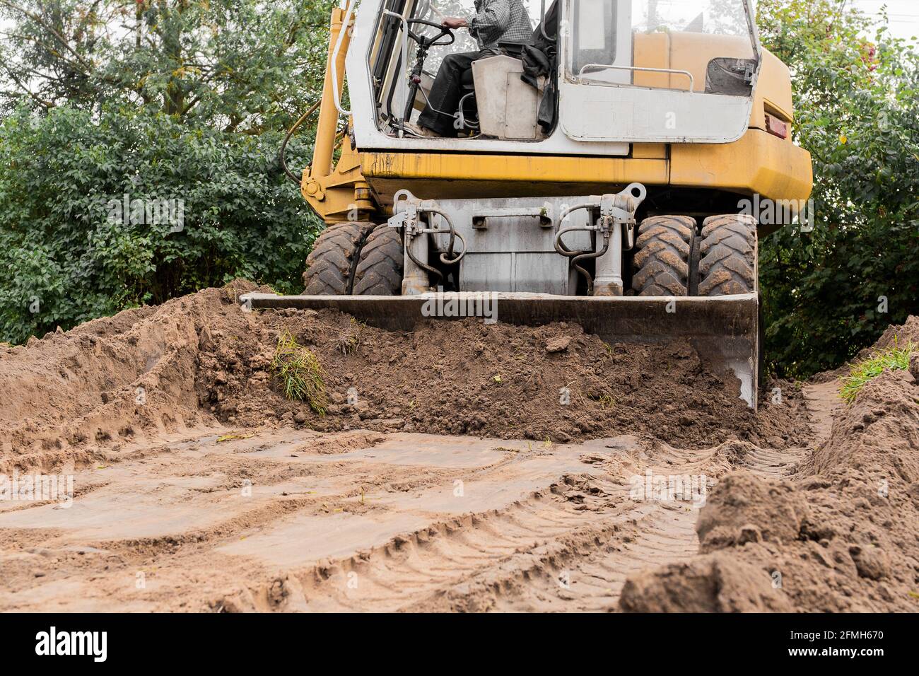 Excavator or bulldozer bucket flattens the ground or road in the ...