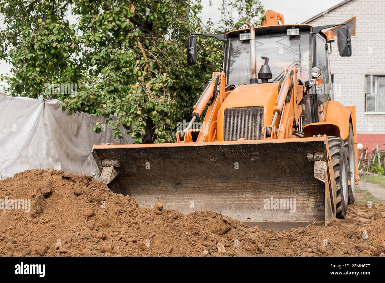 Excavator or bulldozer bucket flattens the ground or road in the ...
