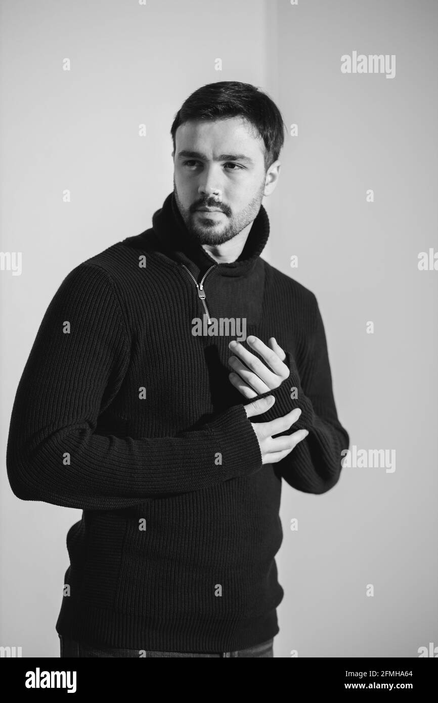 A vertical greyscale shot of a young caucasian male in a black sweater ...