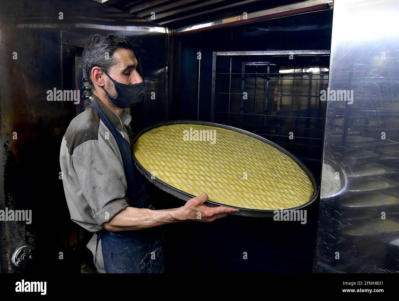Damascus, Syria. 9th May, 2021. A sweet maker prepares traditional ...