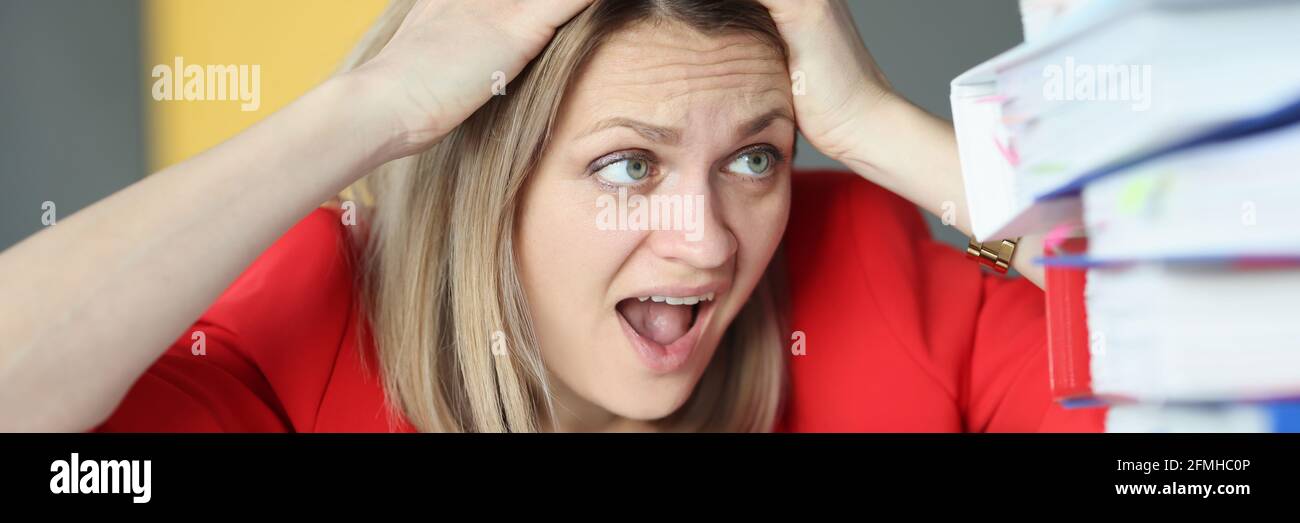 Woman holding her head in front of many paper folders Stock Photo - Alamy