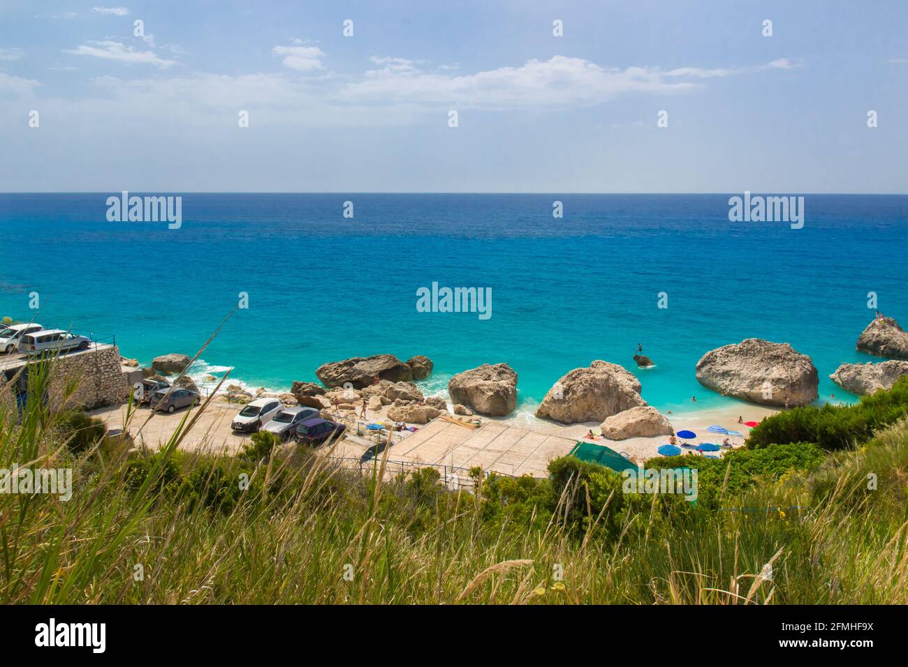 Beautiful small beach in Greece with parked cars Stock Photo - Alamy