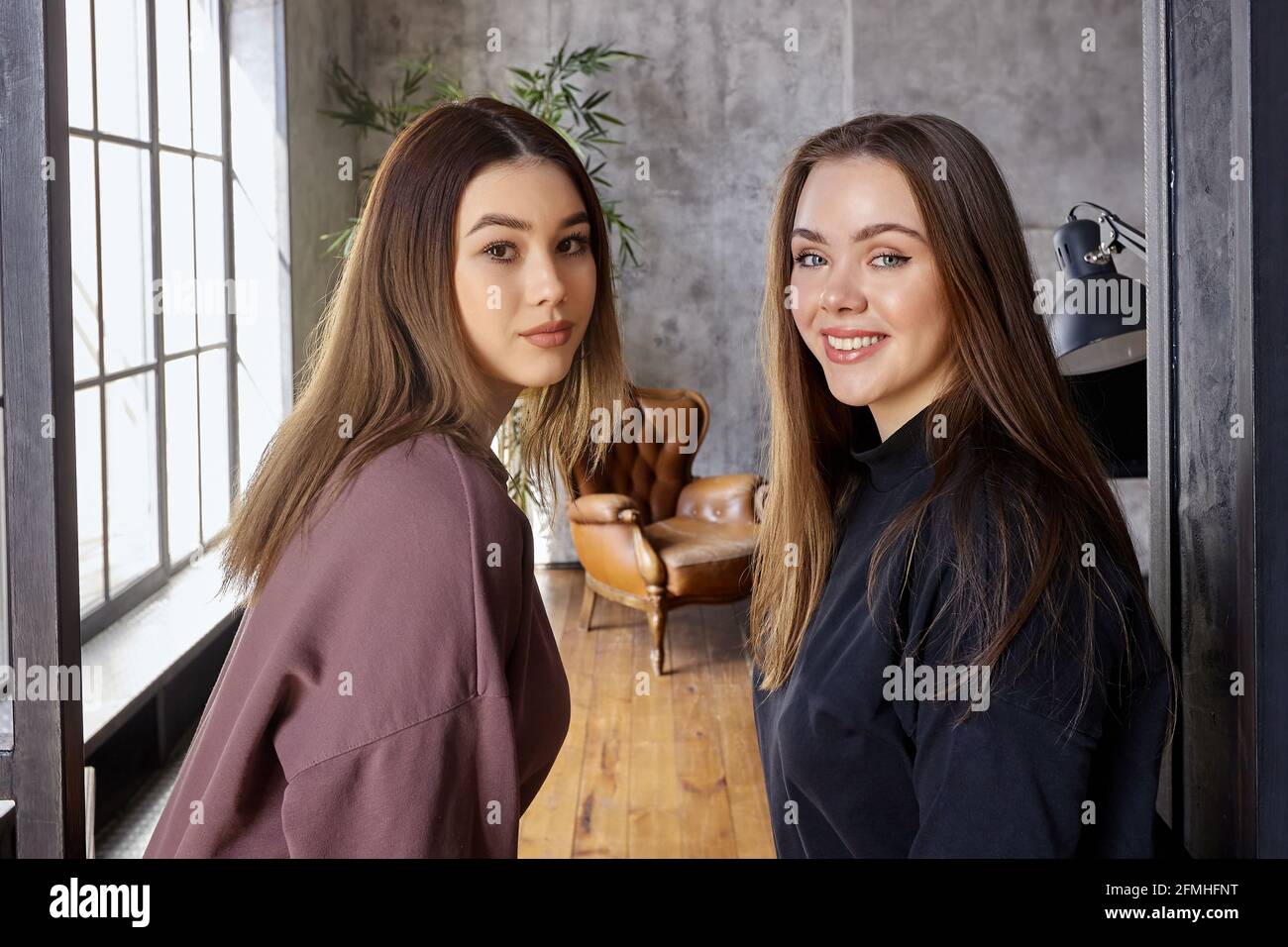 Sad and cheerful young women posing in a loft apartment room Stock ...