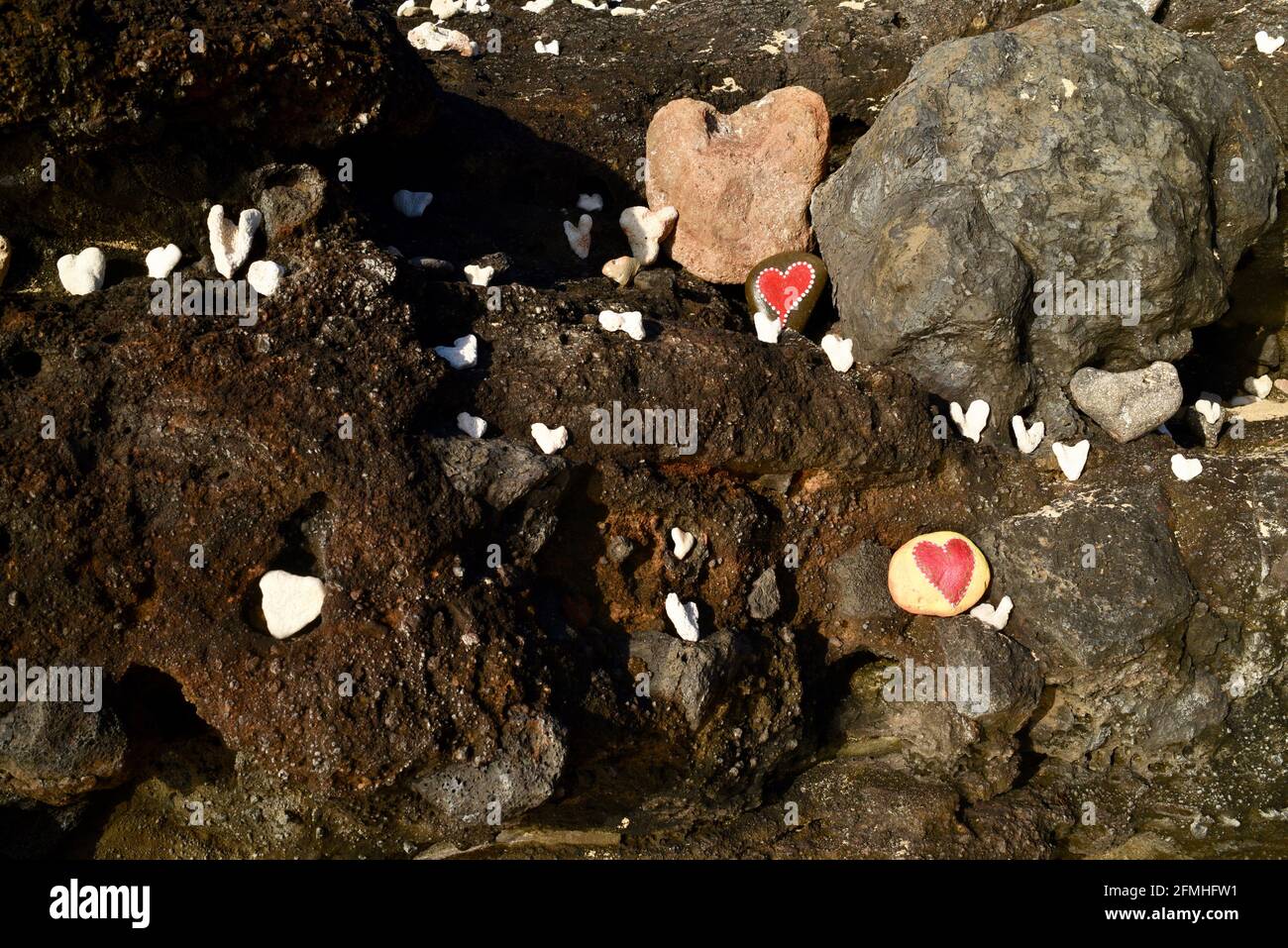Heart shaped coral and stones, painted with bright red "love" hearts ...