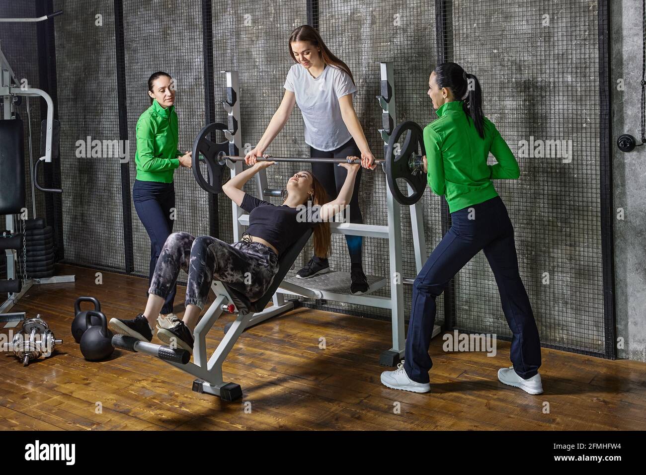 Woman does bench press when others assist her Stock Photo - Alamy