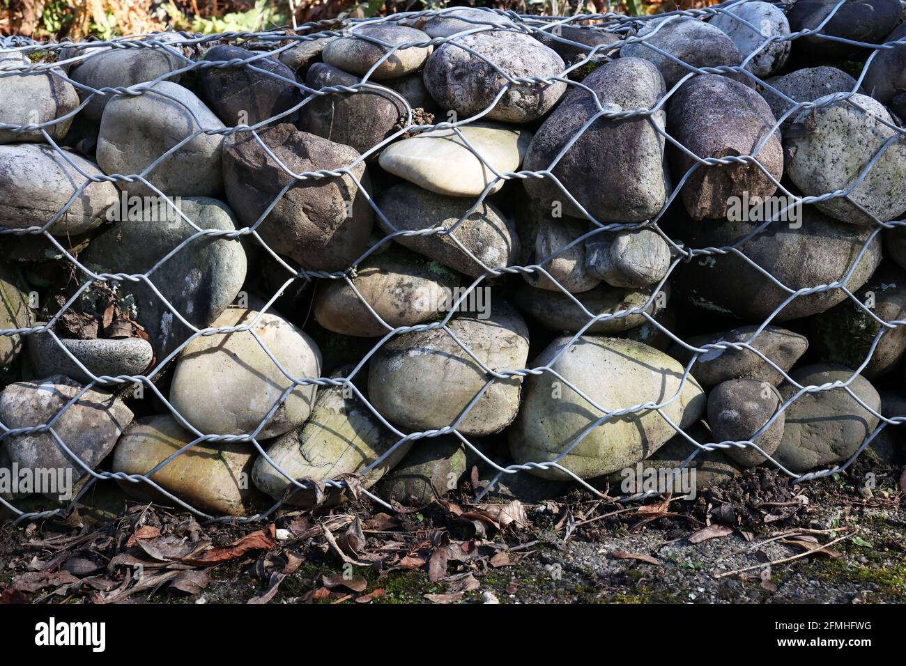 A wall of round stones held by metal mesh Stock Photo - Alamy